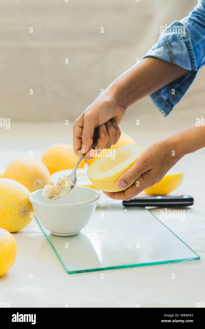 Melon berries on the kitchen table, hands cut melon into halves . glass ...