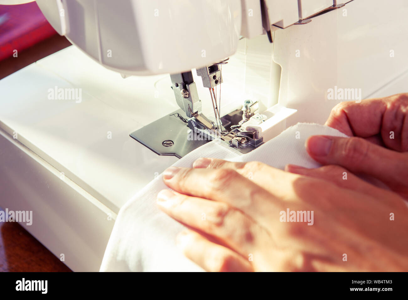 Young woman working in a sewing studio: sewing with a serger ...