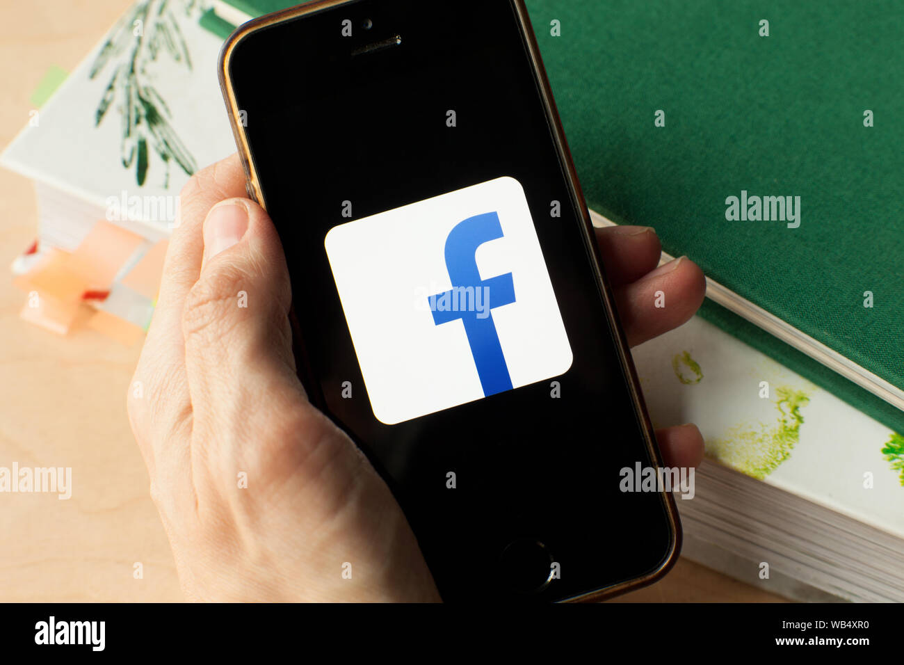Hand holding a smartphone with a Facebook icon on screen. IPhone with a ...