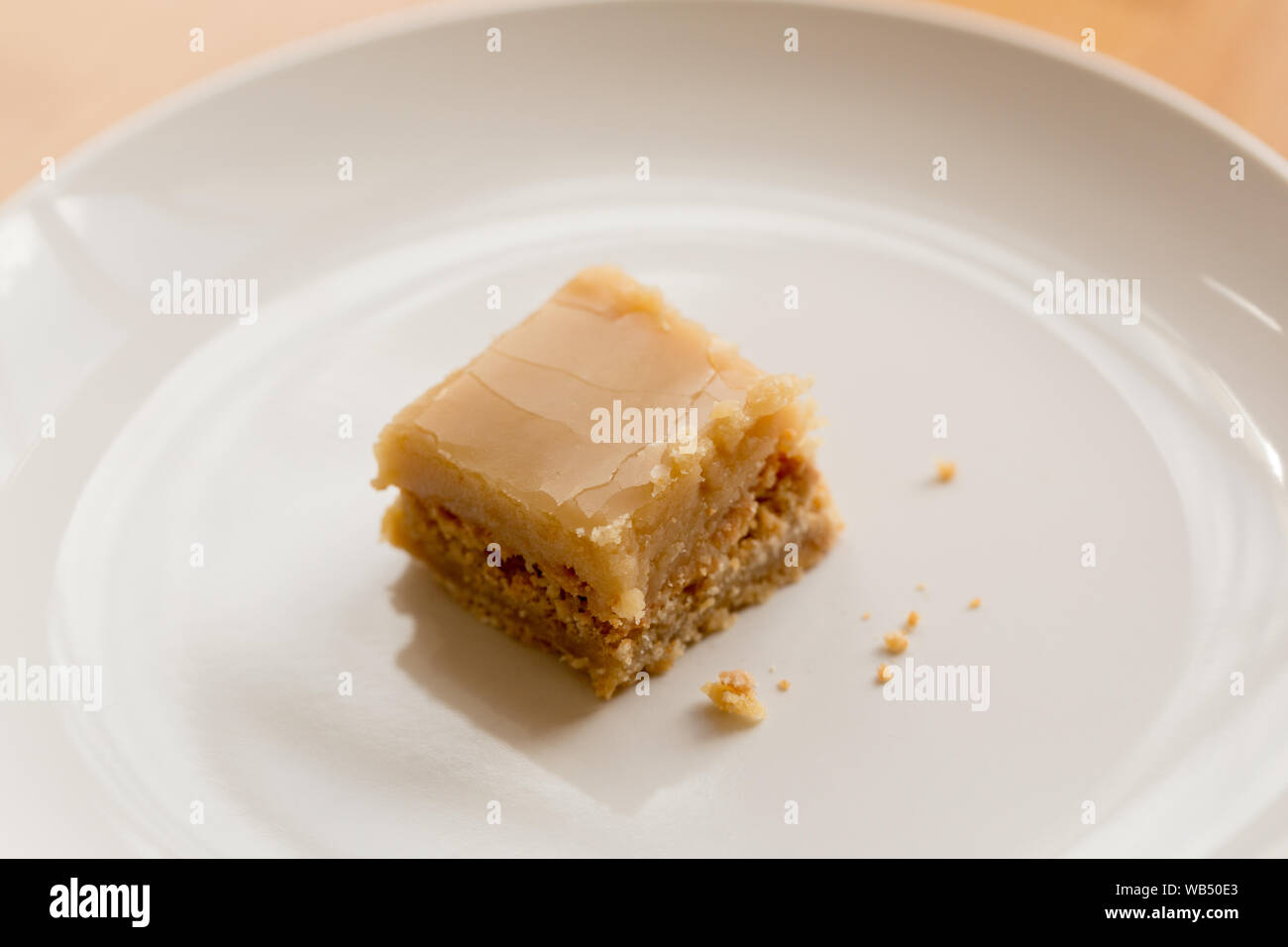 One piece of butterscotch square on white plate with crumbs Stock Photo ...