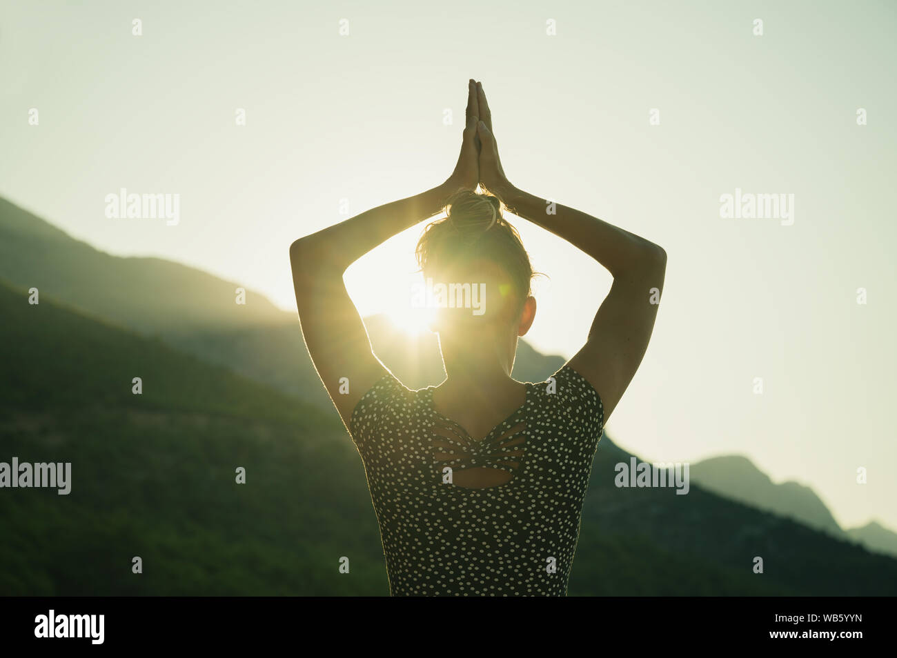View from behind of a young woman making yoga asana with the morning ...