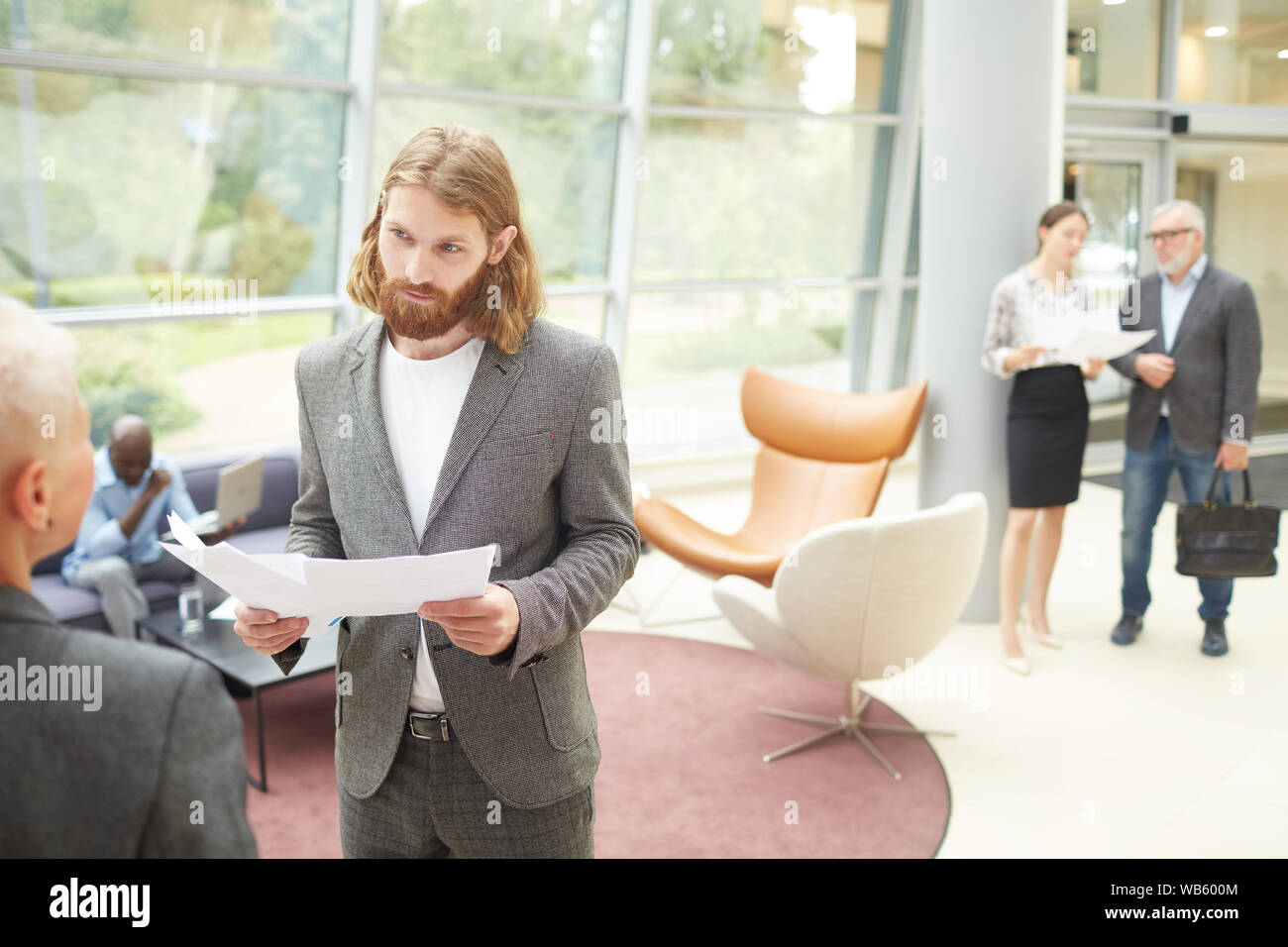 Portrait of successful businessman talking to client standing in modern ...