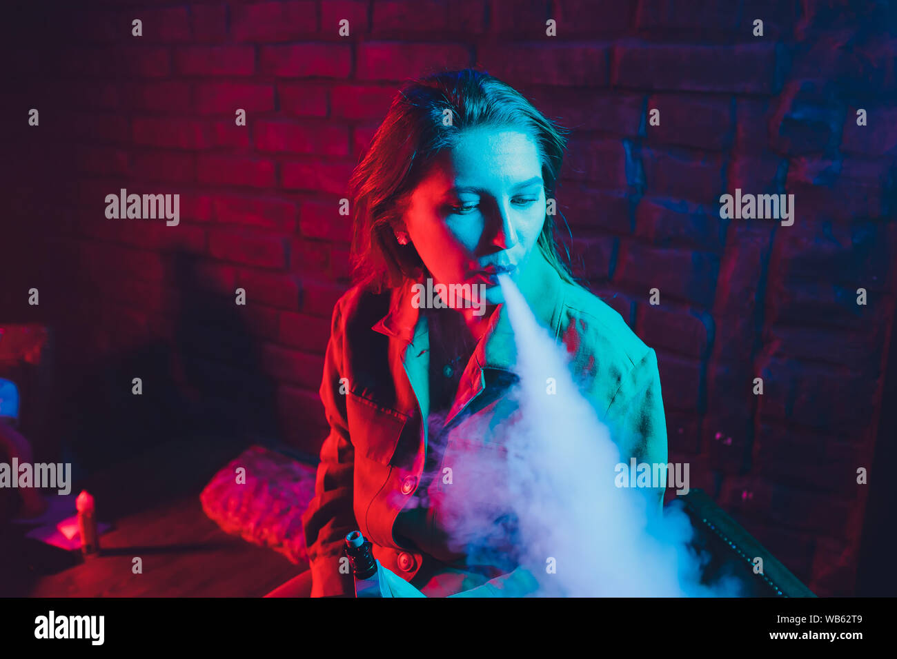 woman smokes a e-cigarette lying on the bed in the room. Smoker's ...