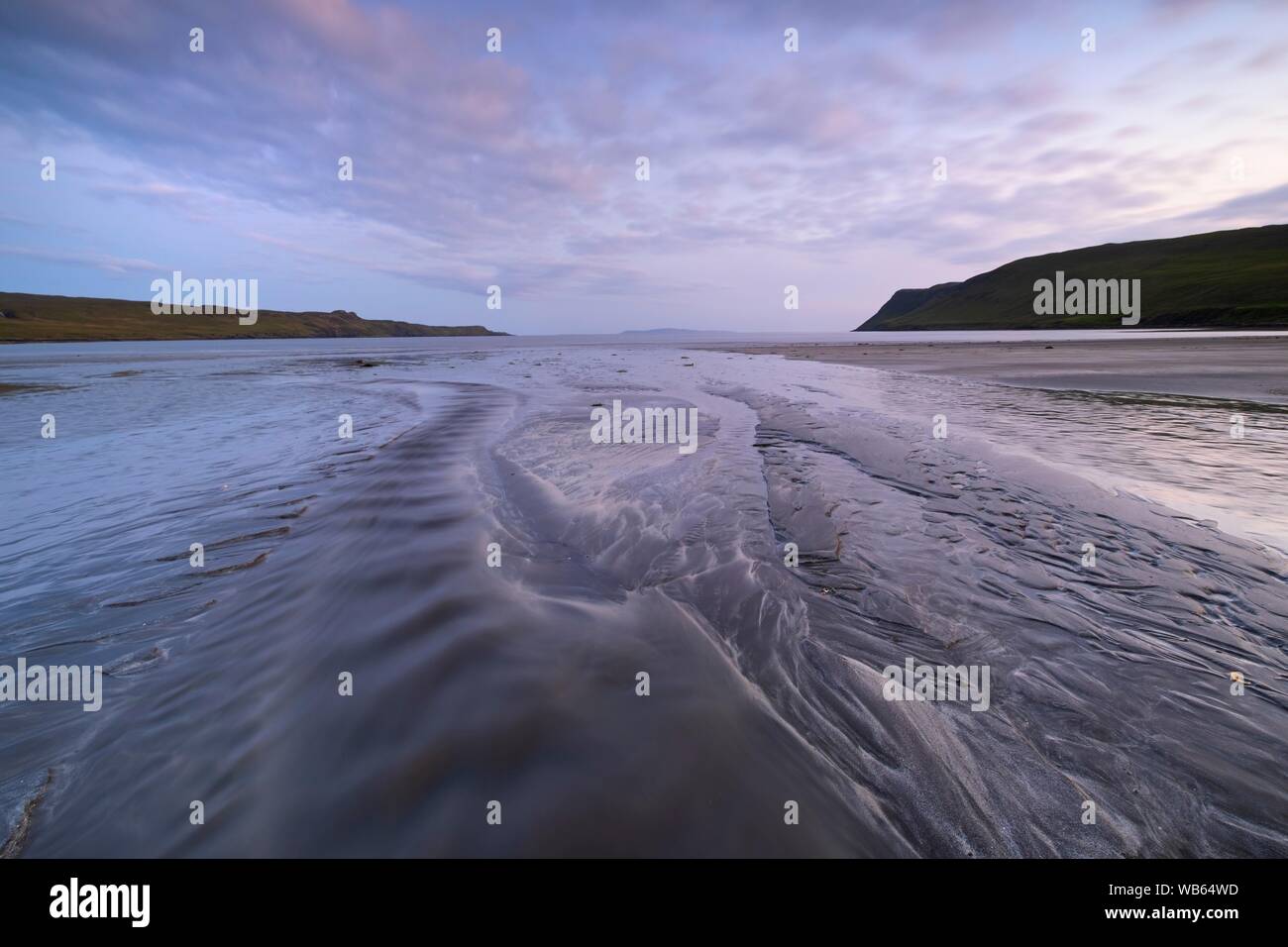 Stream flows over sandy beach into the sea and forms structures, low ...