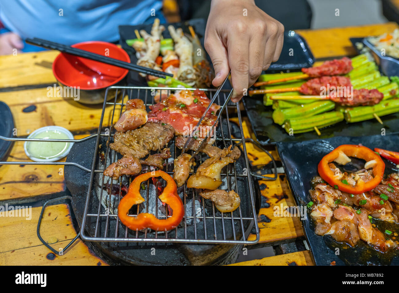 Human hand using tongs while grilling meat and bell pepper Stock Photo ...