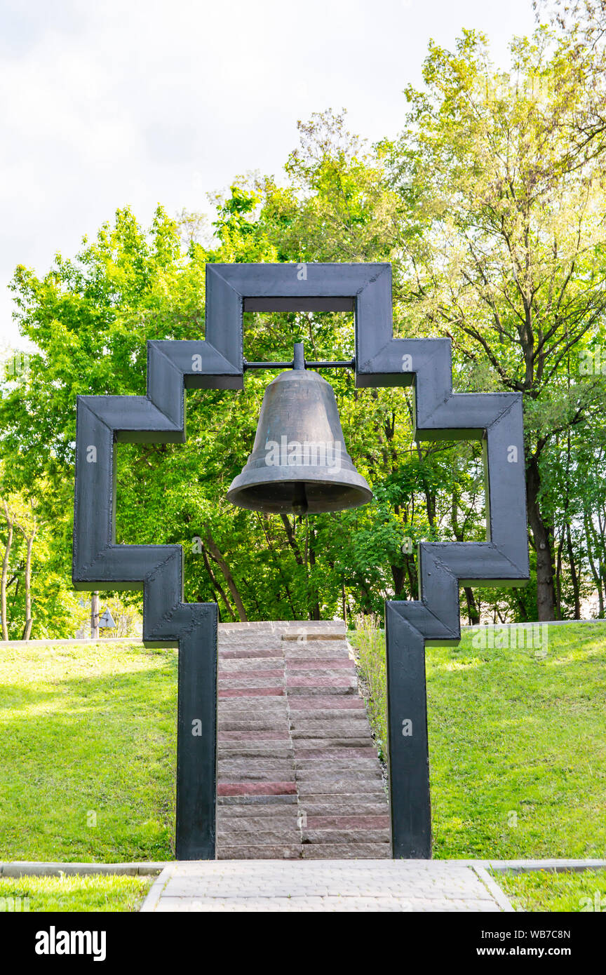 Christian cross with a bell inside on a green grass background on a ...