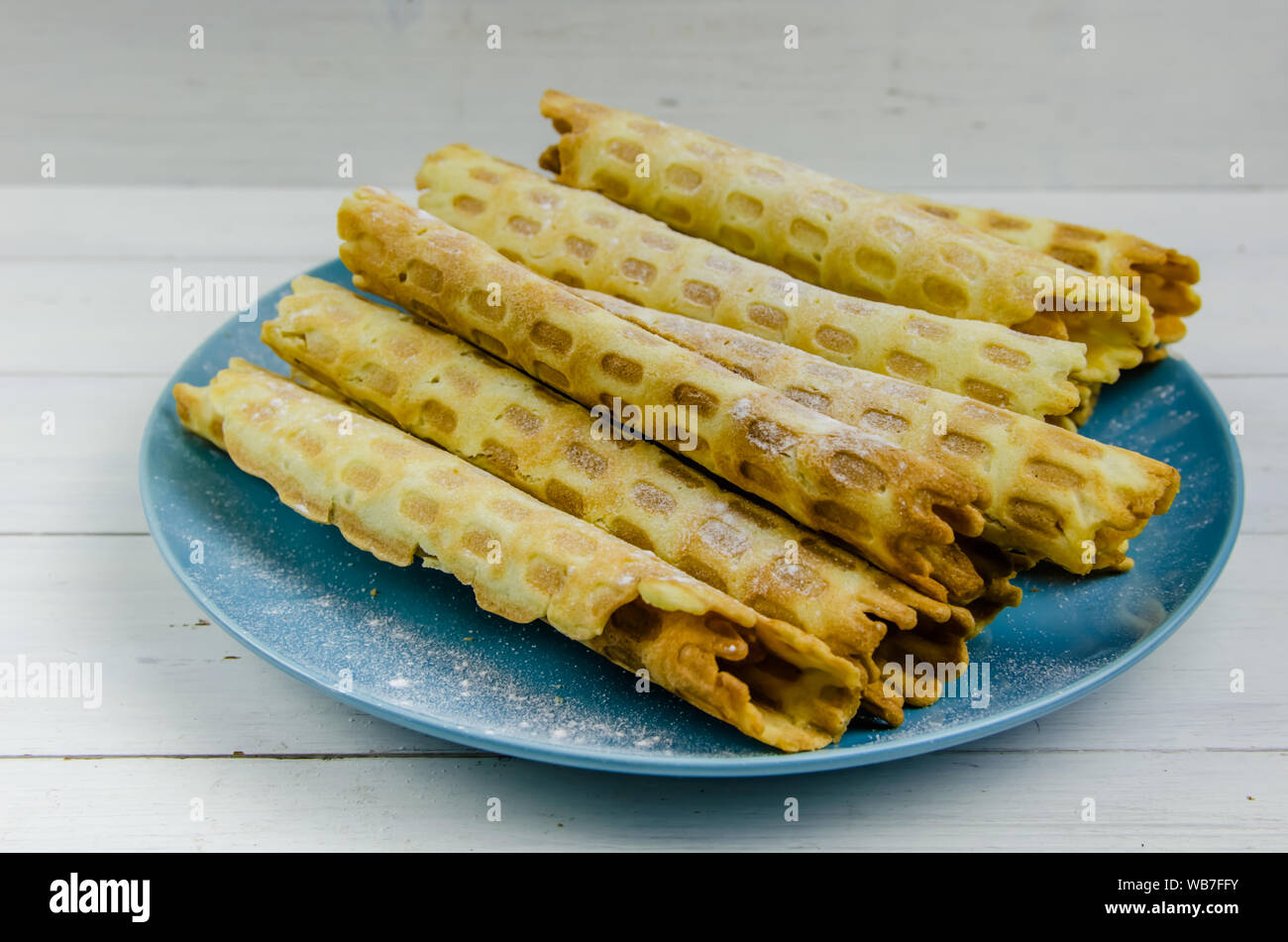 homemade waffle tubes on a blue plate on white background Stock Photo ...