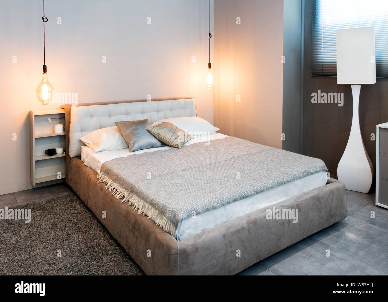 Illuminated interior of a neutral modern bedroom with neat double divan ...