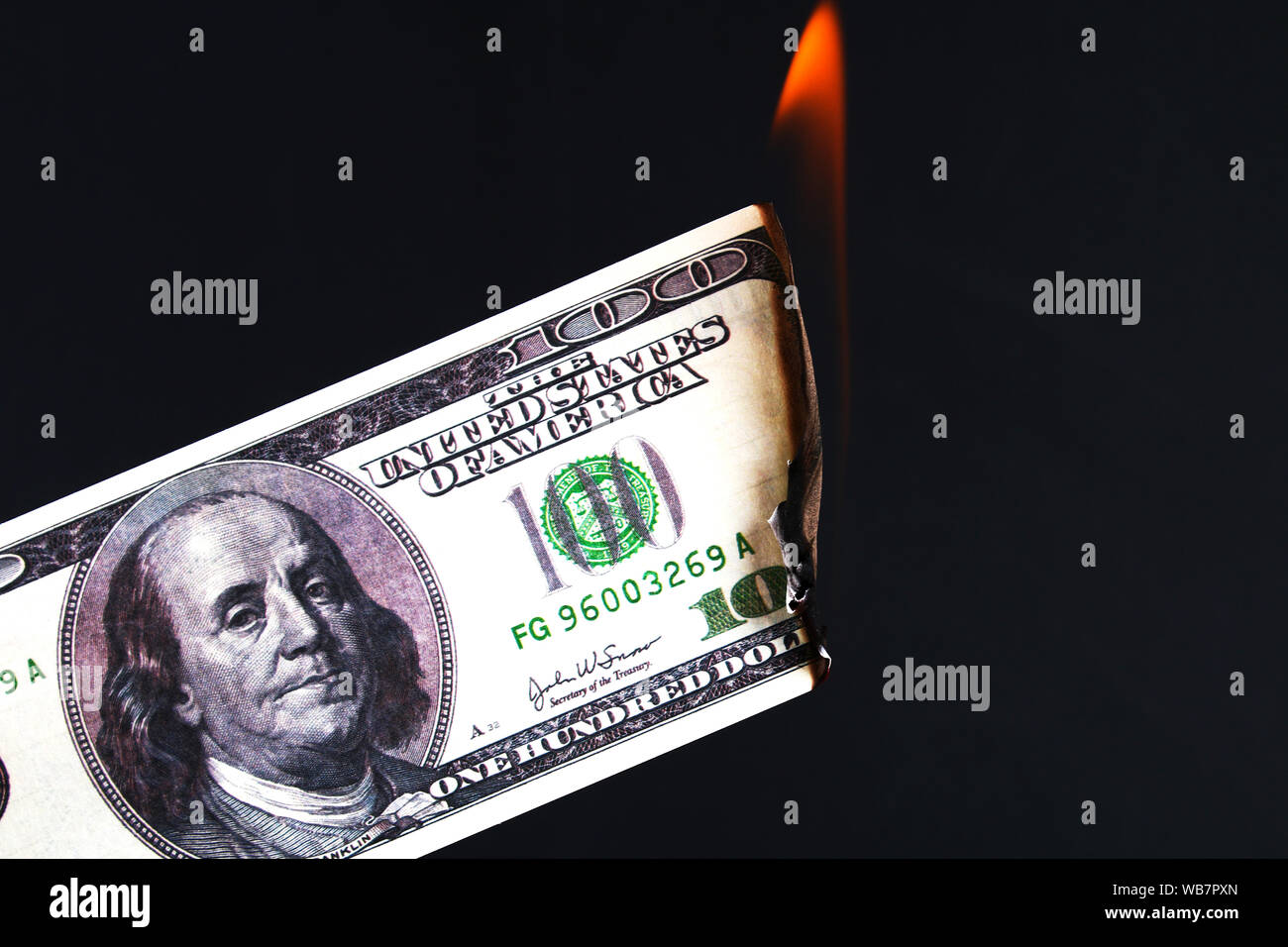 one hundred American dollar burning in fire flame on black paper ...