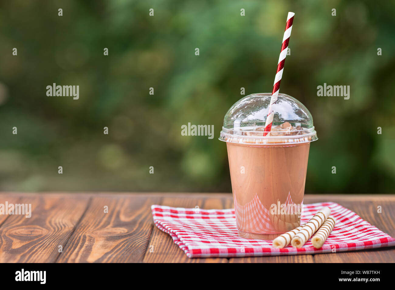 ice chocolate milkshake in disposable plastic cup with wafer rolls on ...