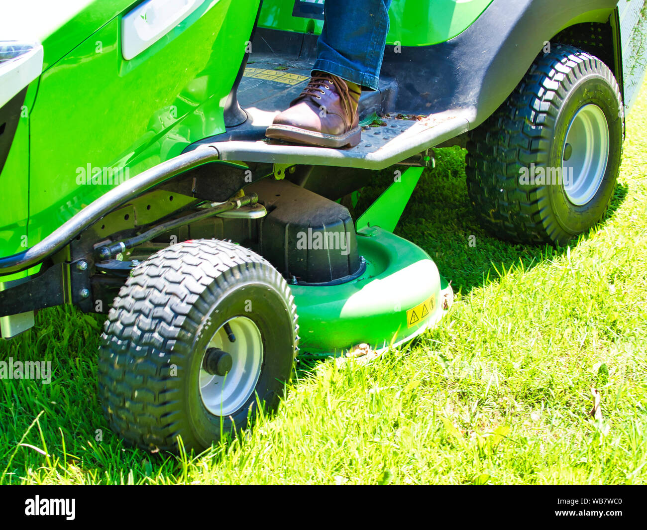 Senior man 75 old years driving a tractor lawn mower in garden with ...