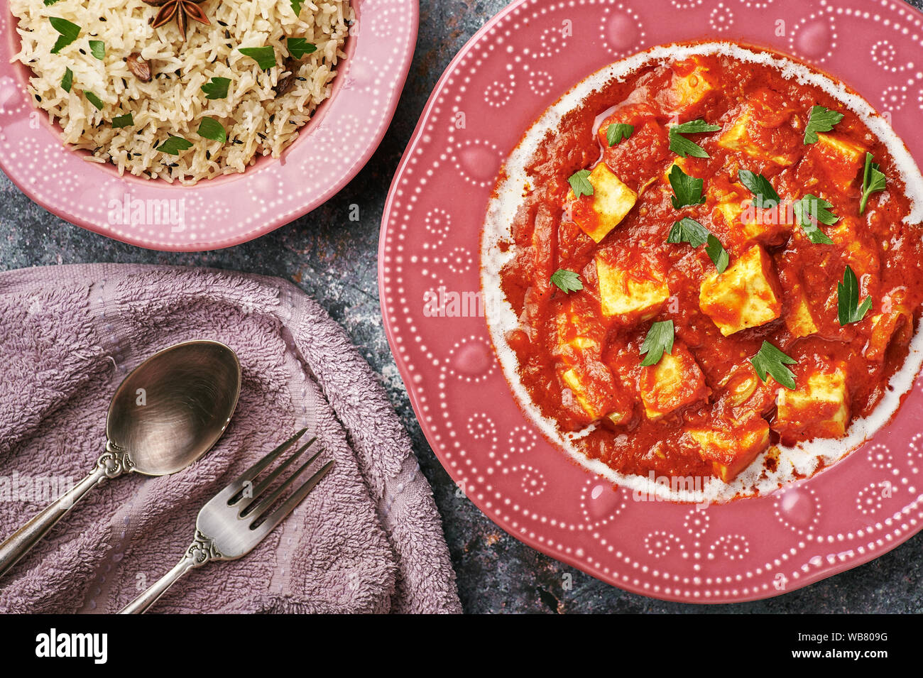 Paneer Makhani, Jeera Rice and paratha in pink plate on dark background ...