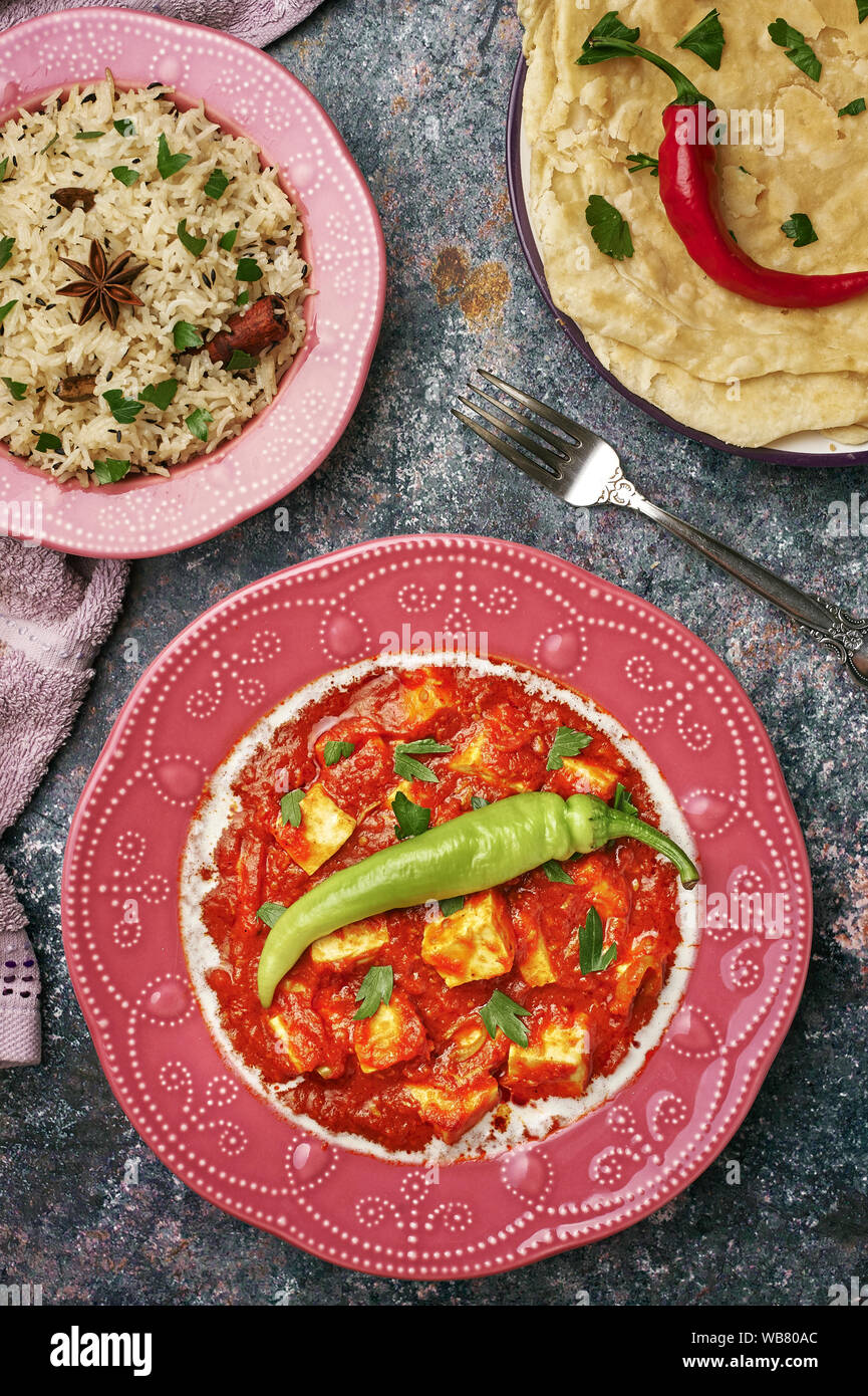 Paneer Makhani, Jeera Rice and paratha in pink plate on dark background ...
