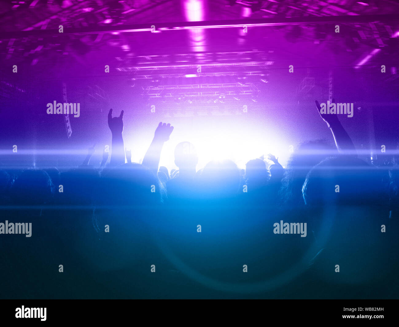 Colourful shot taken inside a concert venue, people silhouettes are ...