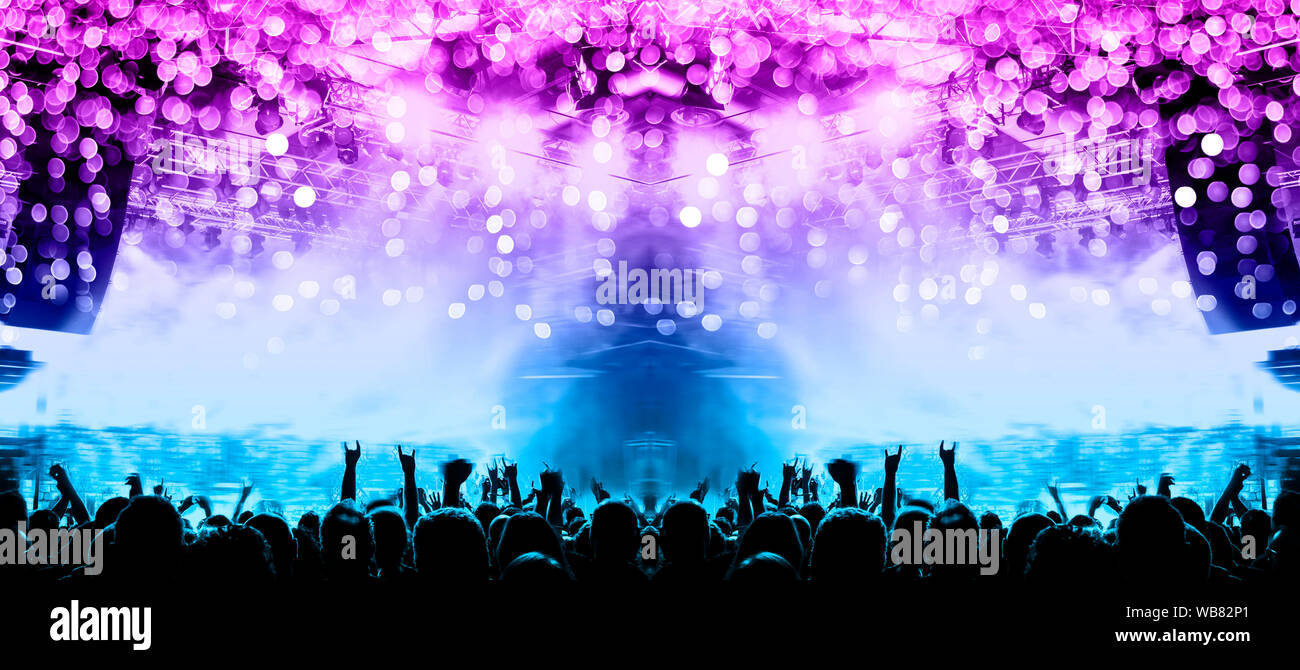 Colourful shot taken inside a concert venue, people silhouettes are ...