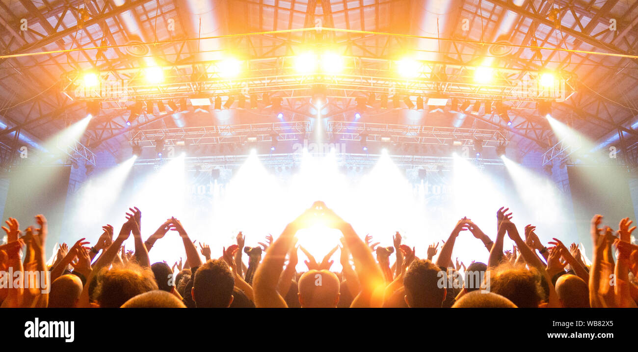 Colourful shot taken inside a concert venue, people silhouettes are ...