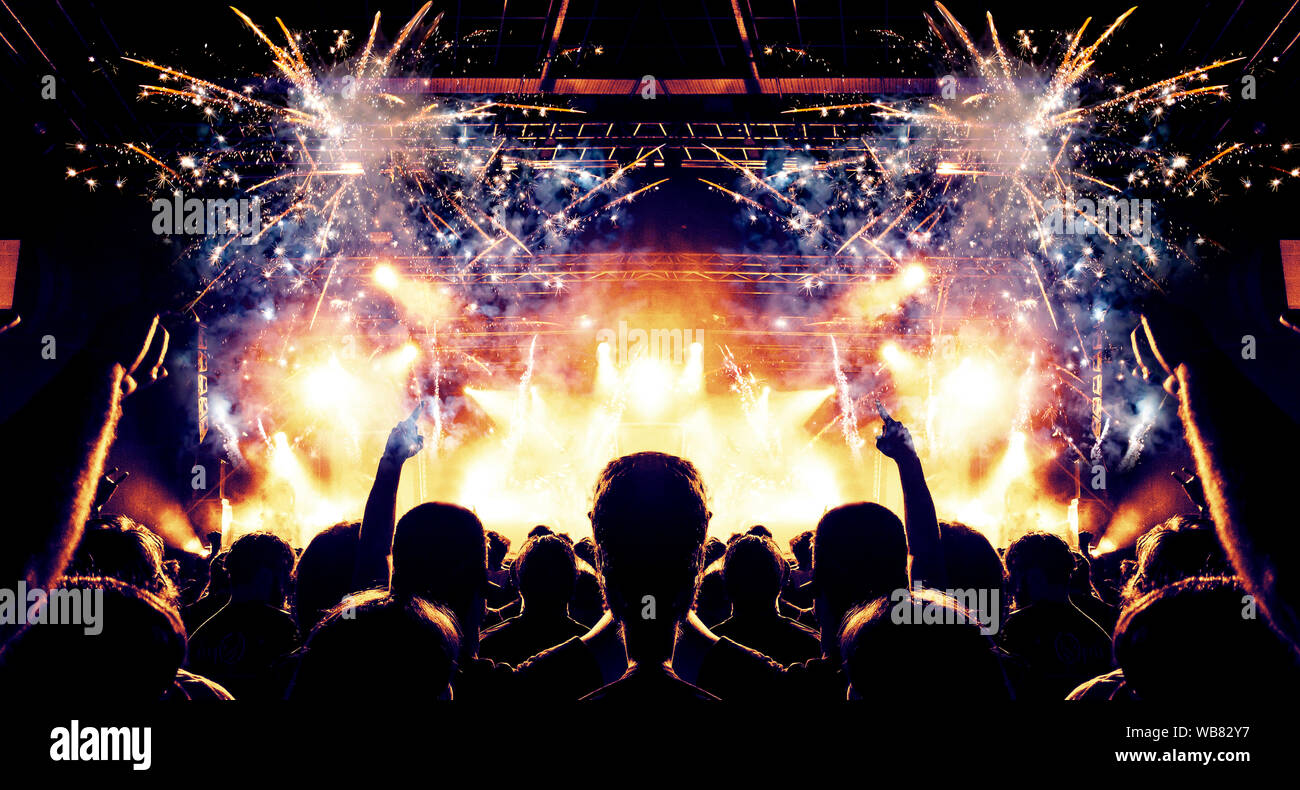 Colourful shot taken inside a concert venue, people silhouettes are ...