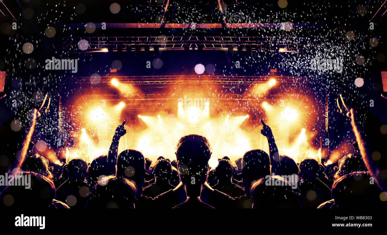 Colourful shot taken inside a concert venue, people silhouettes are ...