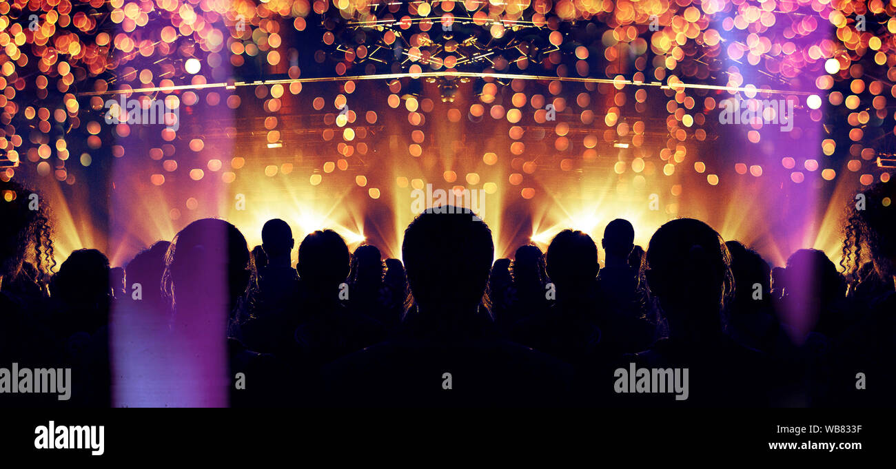 Colourful shot taken inside a concert venue, people silhouettes are ...