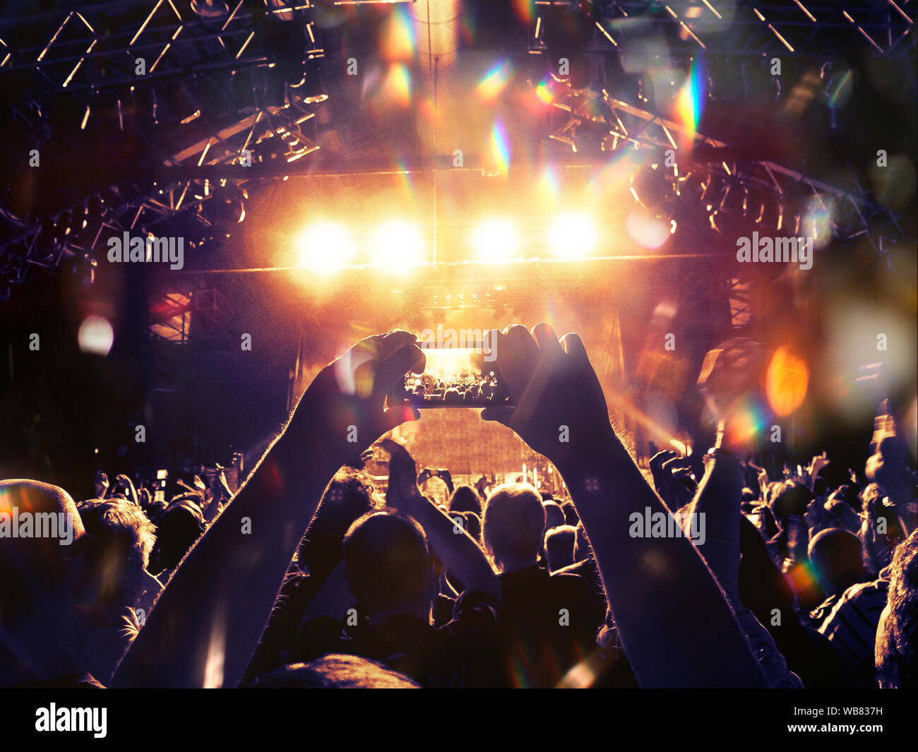 Colourful shot taken inside a concert venue, people silhouettes are ...