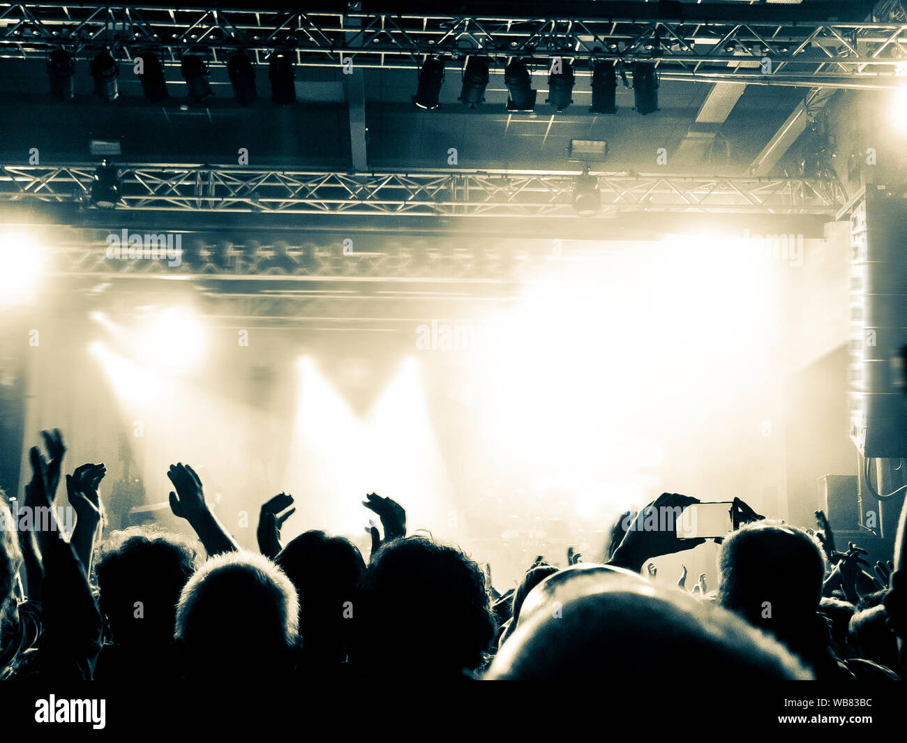 Colourful shot taken inside a concert venue, people silhouettes are ...