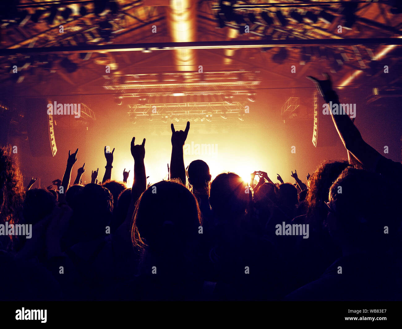 Colourful shot taken inside a concert venue, people silhouettes are ...