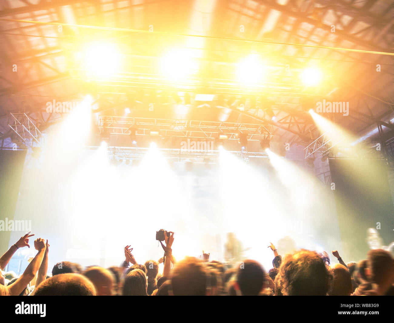 Colourful shot taken inside a concert venue, people silhouettes are ...