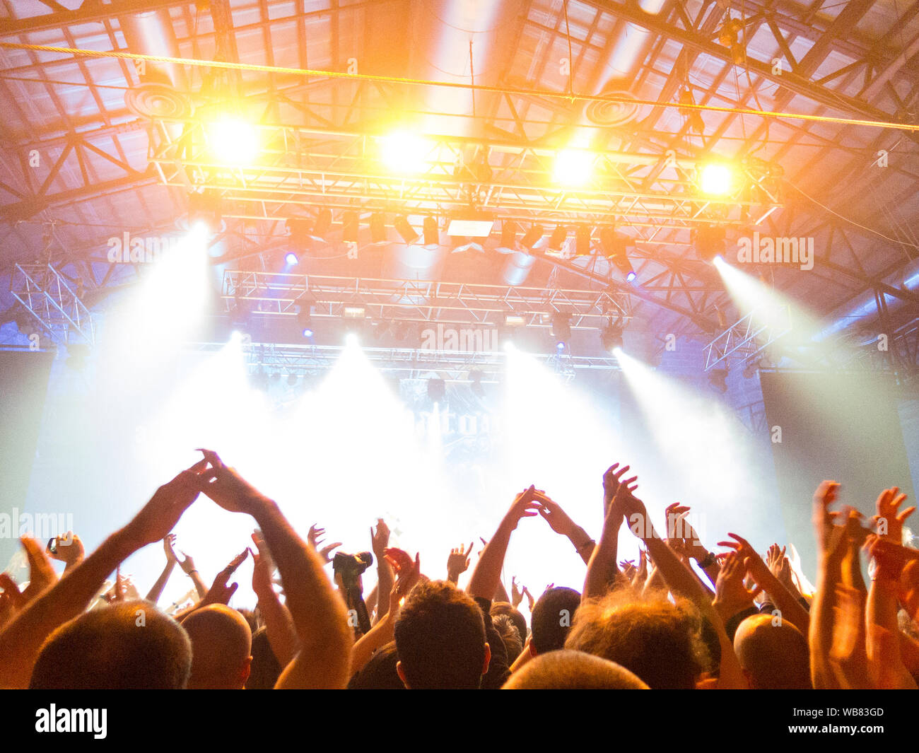 Colourful shot taken inside a concert venue, people silhouettes are ...