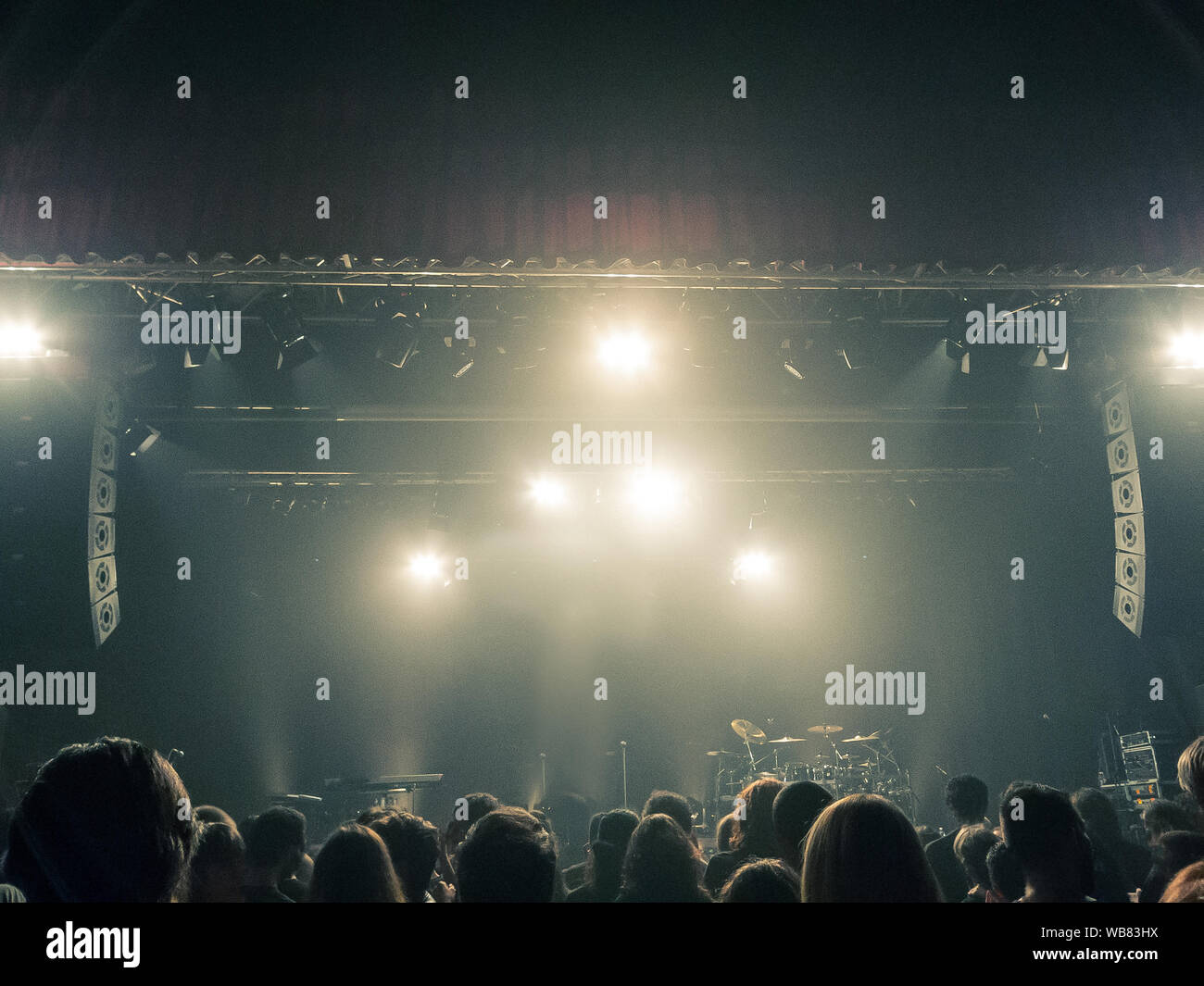 Colourful shot taken inside a concert venue, people silhouettes are ...