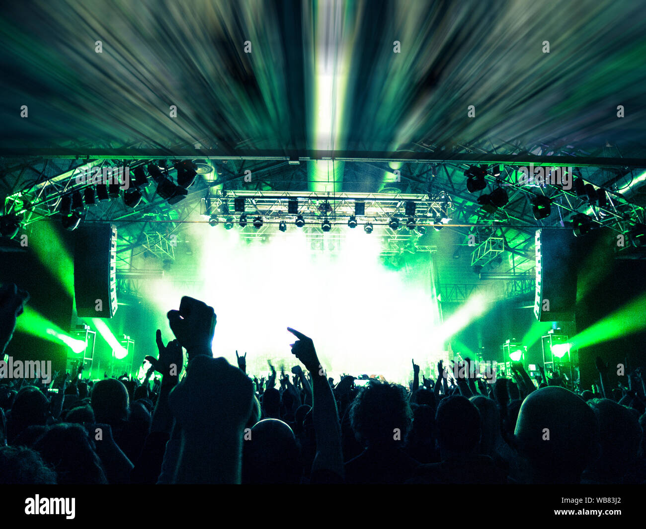 Colourful shot taken inside a concert venue, people silhouettes are ...