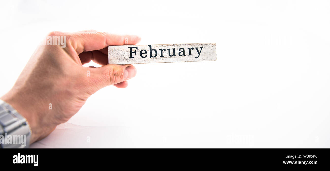 February - A hand holding calendar month block on white background ...