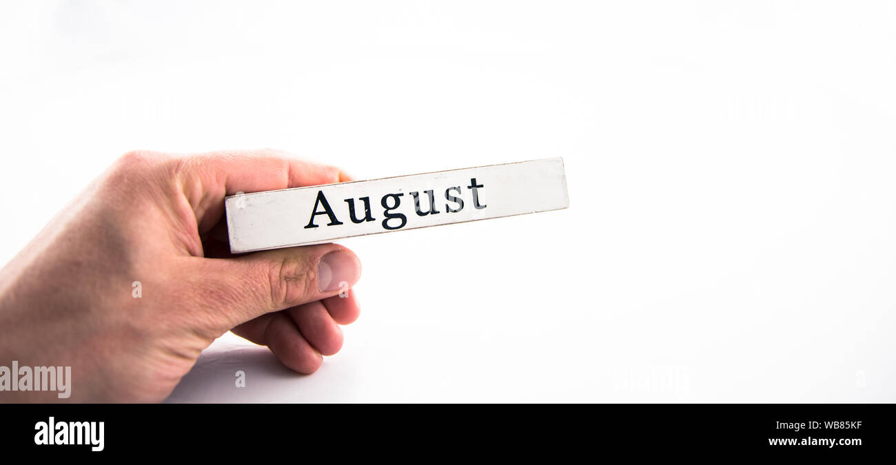 August - A hand holding calendar month block on white background Stock ...