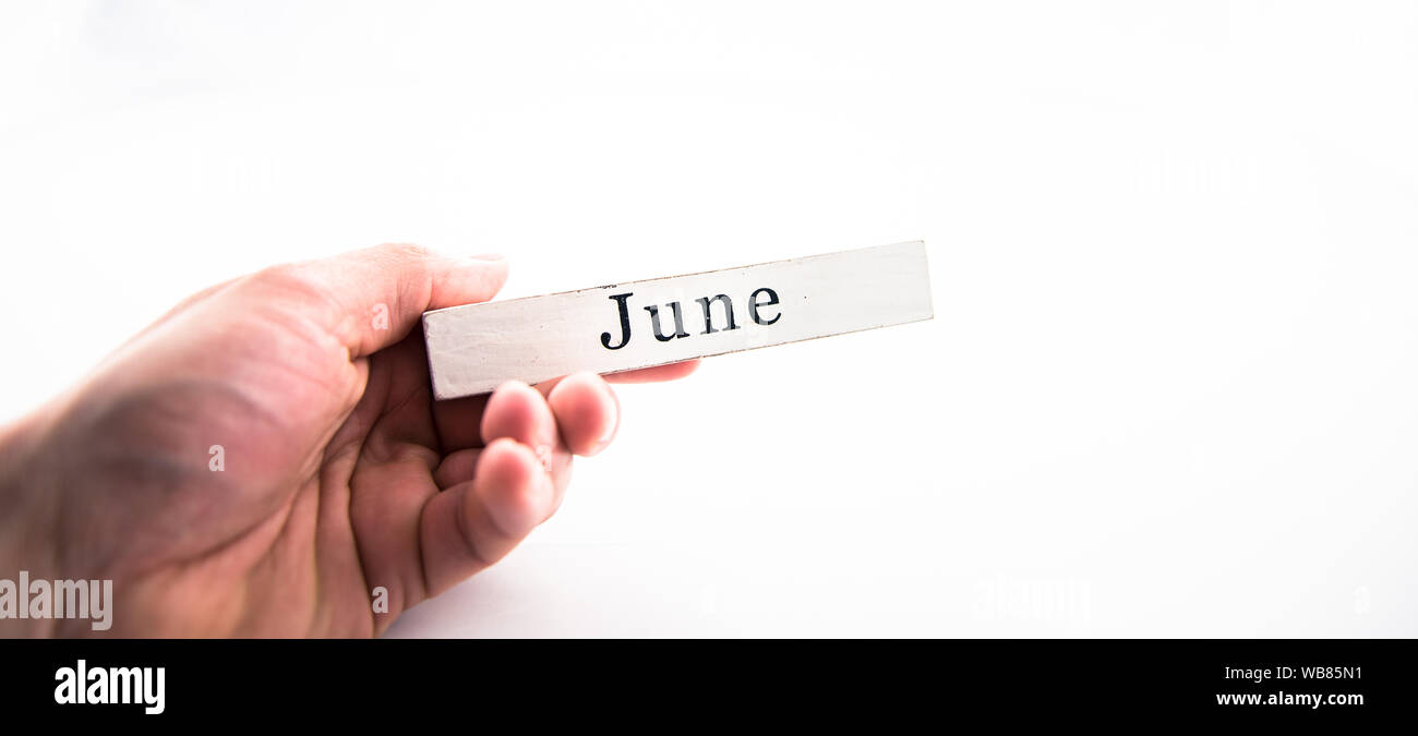 June - A hand holding calendar month block on white background Stock ...