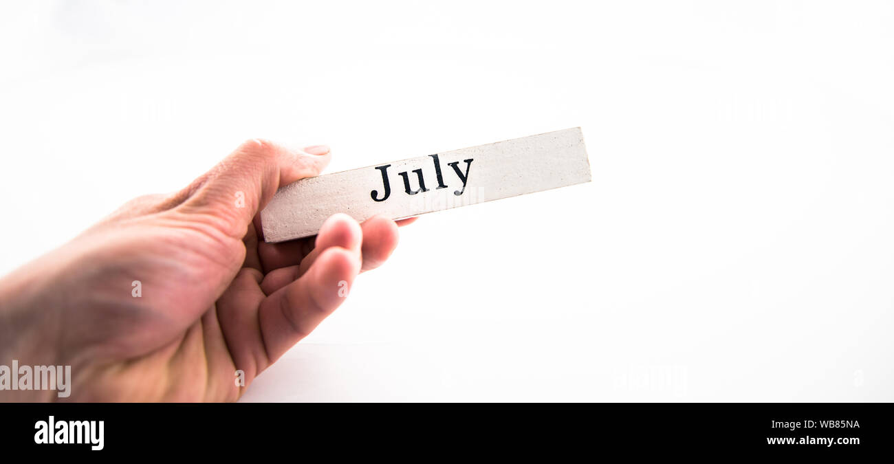 July - A hand holding calendar month block on white background Stock ...