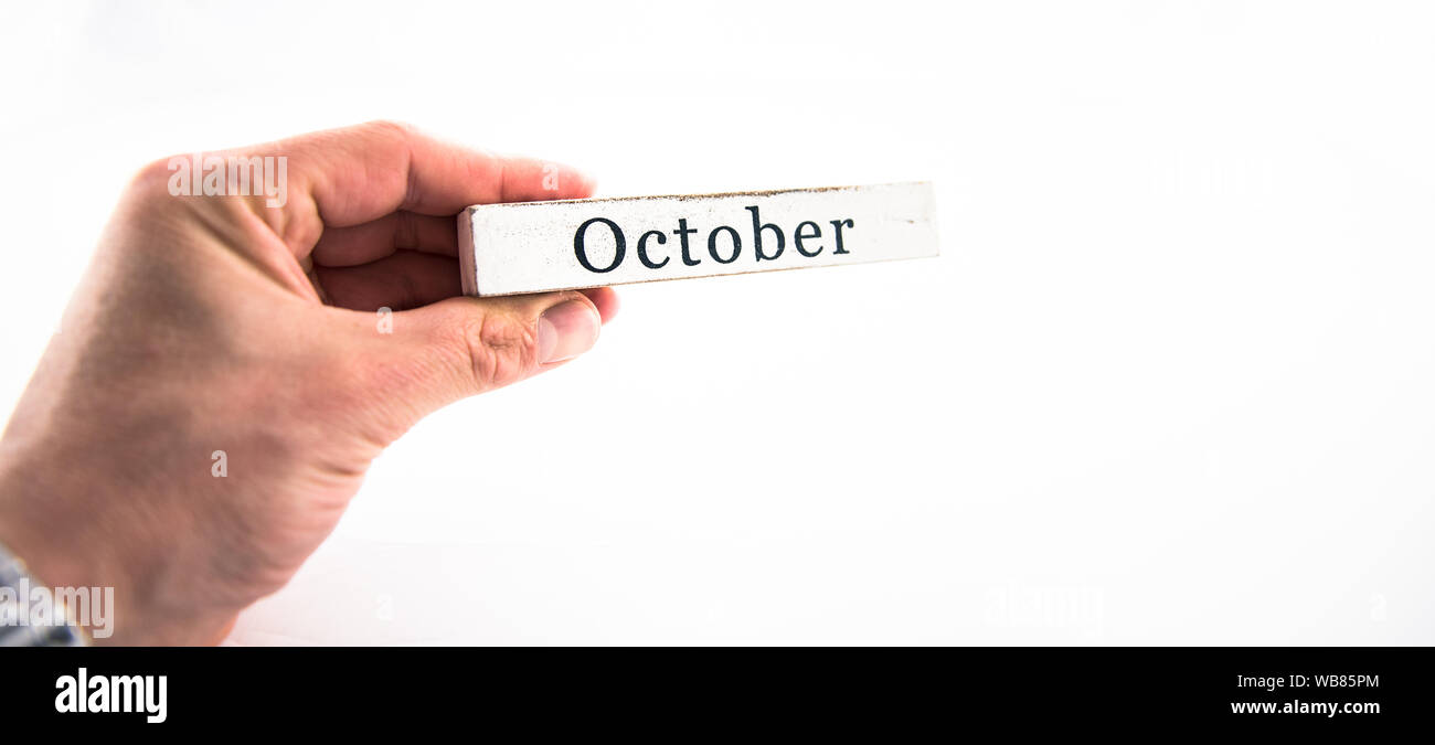 October - A hand holding calendar month block on white background Stock ...