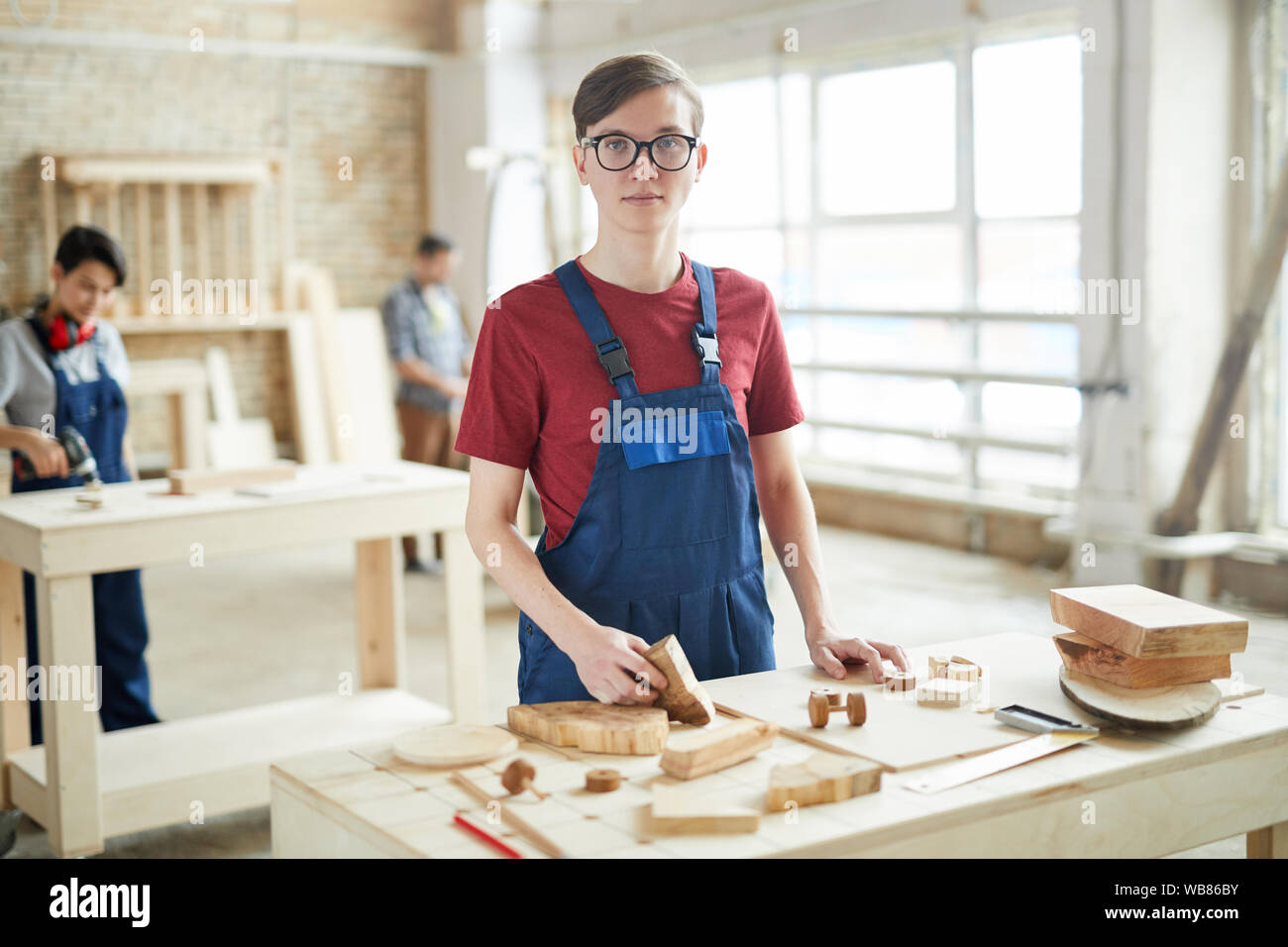 Waist up portrait of young carpenter looking at camera while working ...