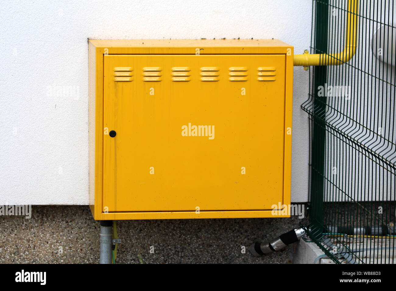 Large yellow metal natural gas connection box mounted on white wall of ...