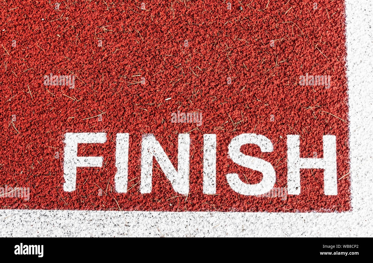 Bold text FINISH is painted at the finish line on a red track in white ...