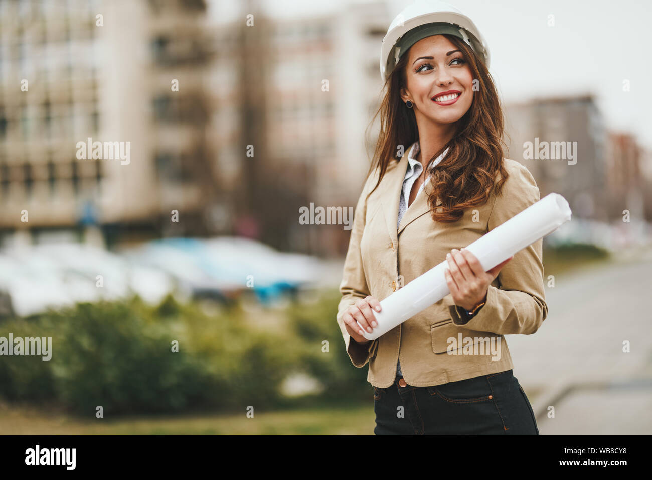 Beautiful young female engineer with white helmet and blueprints in her ...