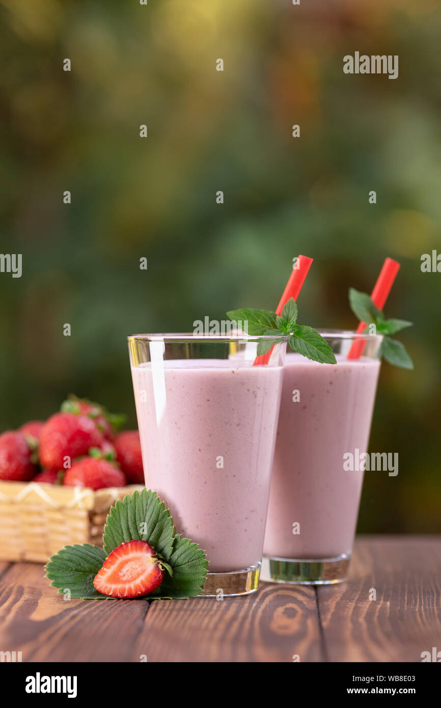 two glasses of strawberry milkshake or smoothie and fresh ripe berries ...