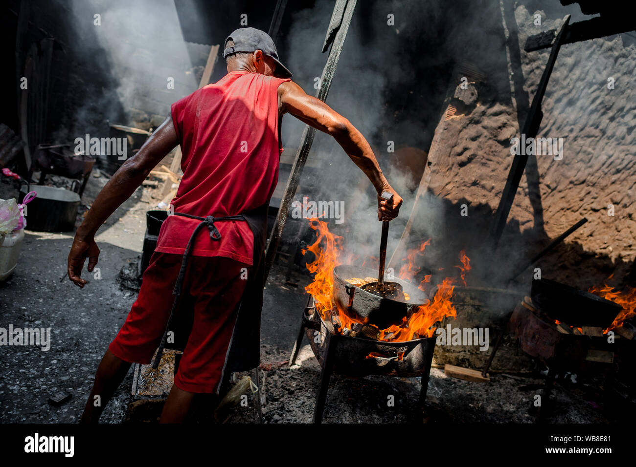 An Afro-Colombian cook fries fish in boiling oil in a street restaurant ...