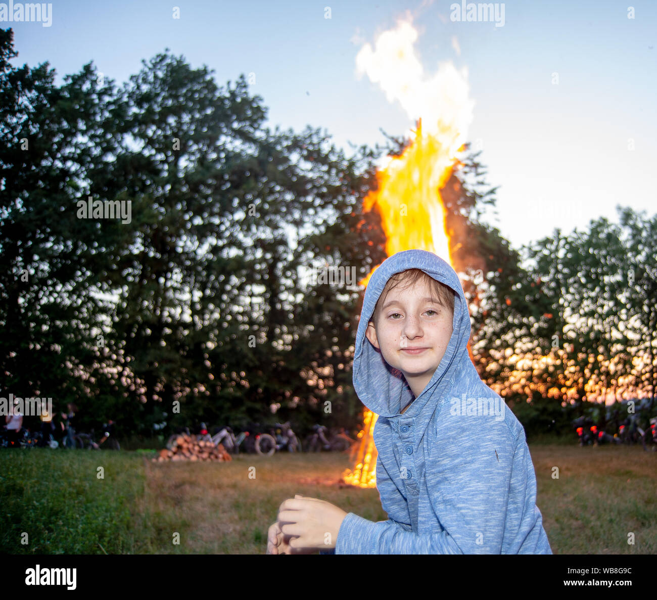 Boy smiling with bonfire in the background Stock Photo - Alamy