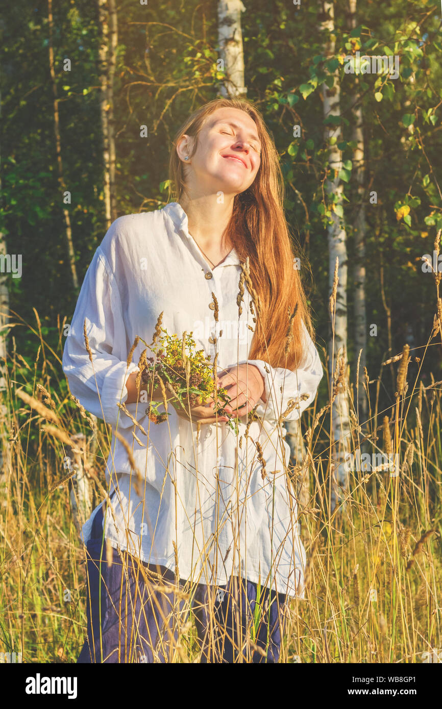 The young girl smiles with a bouquet of wild flowers in the field Stock ...