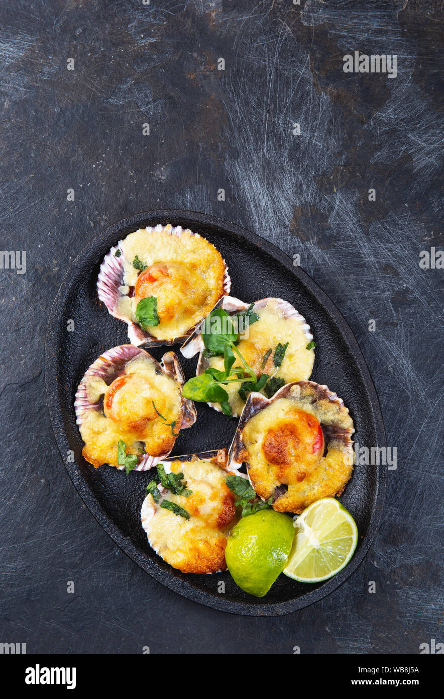 Baked seafood shellfish scallops with cheese and lemon. black ...