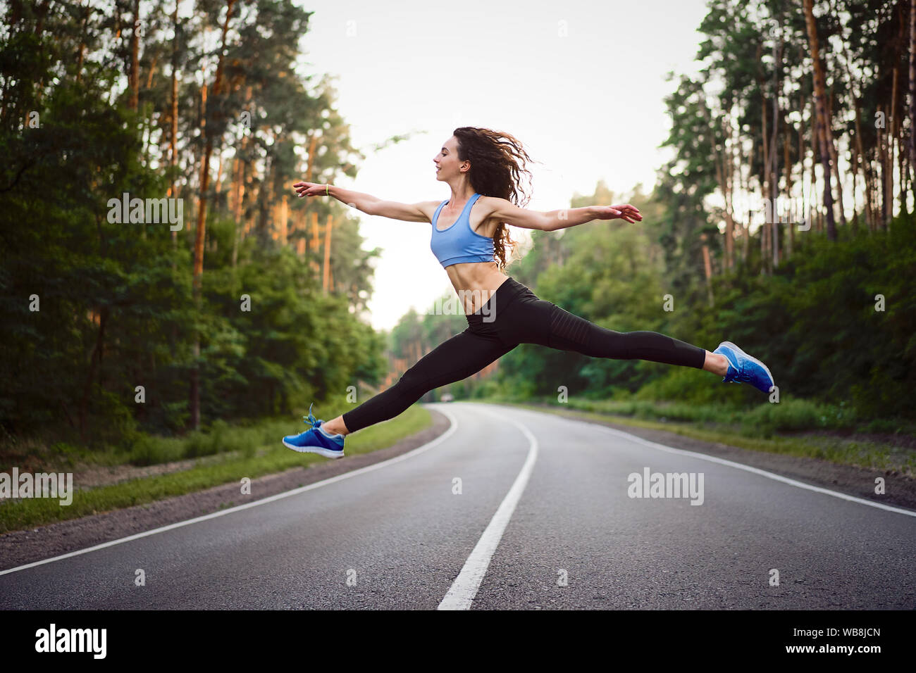 young beautiful brunette girl jumping in twine with background asphalt ...