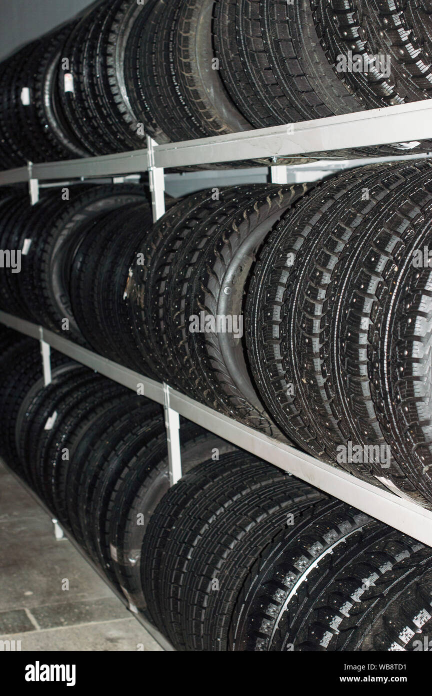 A rack with new, winter, studded and simple rubber car tires. Close-up ...