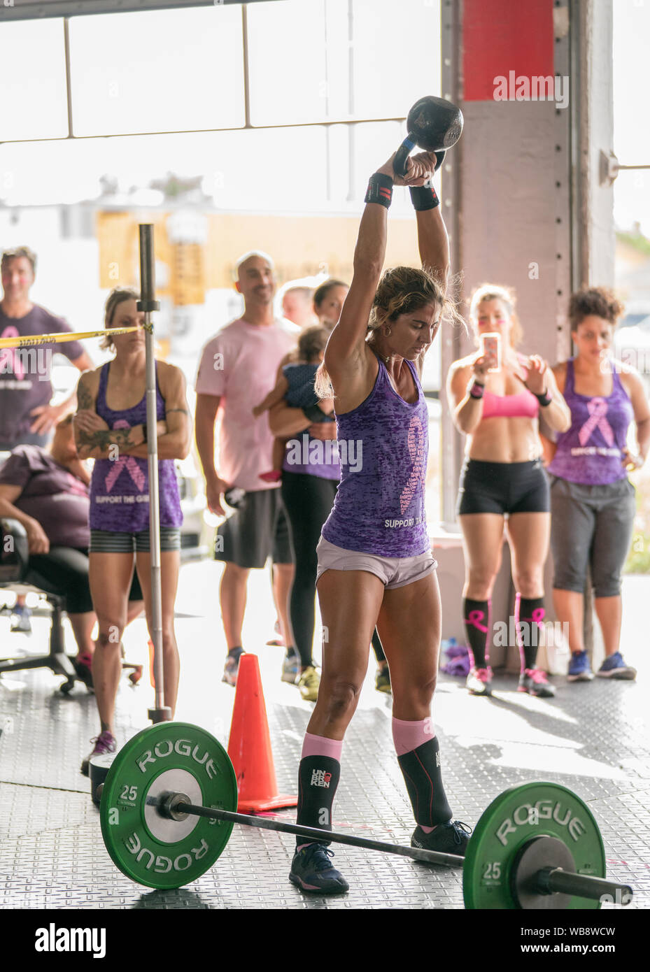 A mixed race female athlete stands near the barbell and is ...