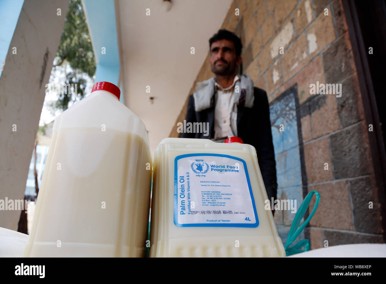Sanaa, Yemen. 25th Aug, 2019. A man stands by his food ration delivered ...