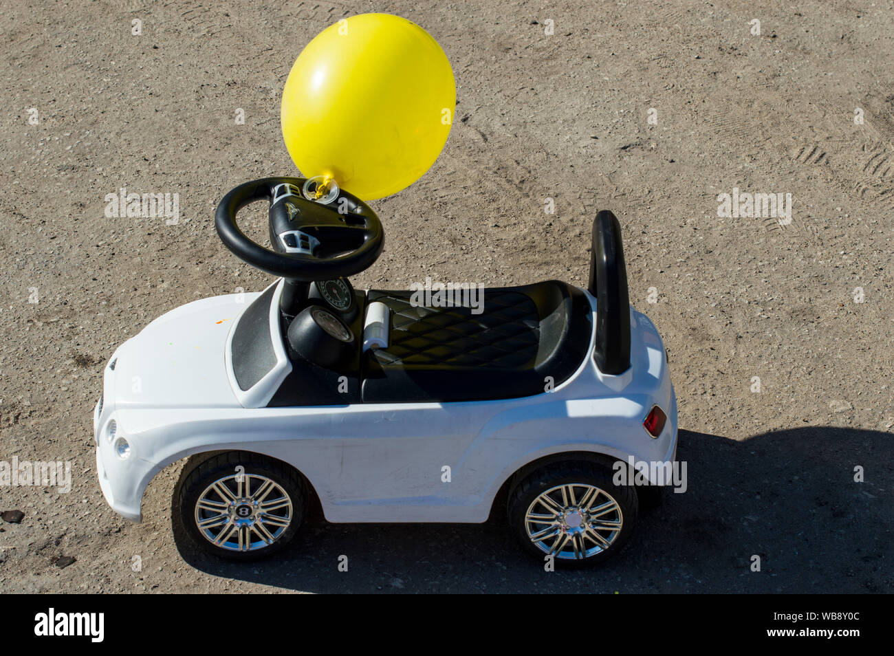 White electric car with a yellow ball in the yard. A toy car for a ...