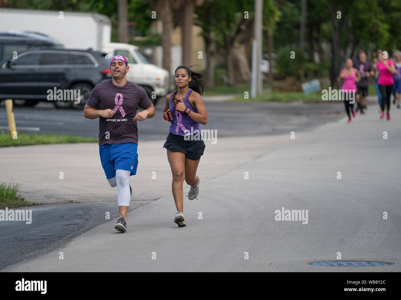 A mixed race young couple is running ahead of a group to the finish ...